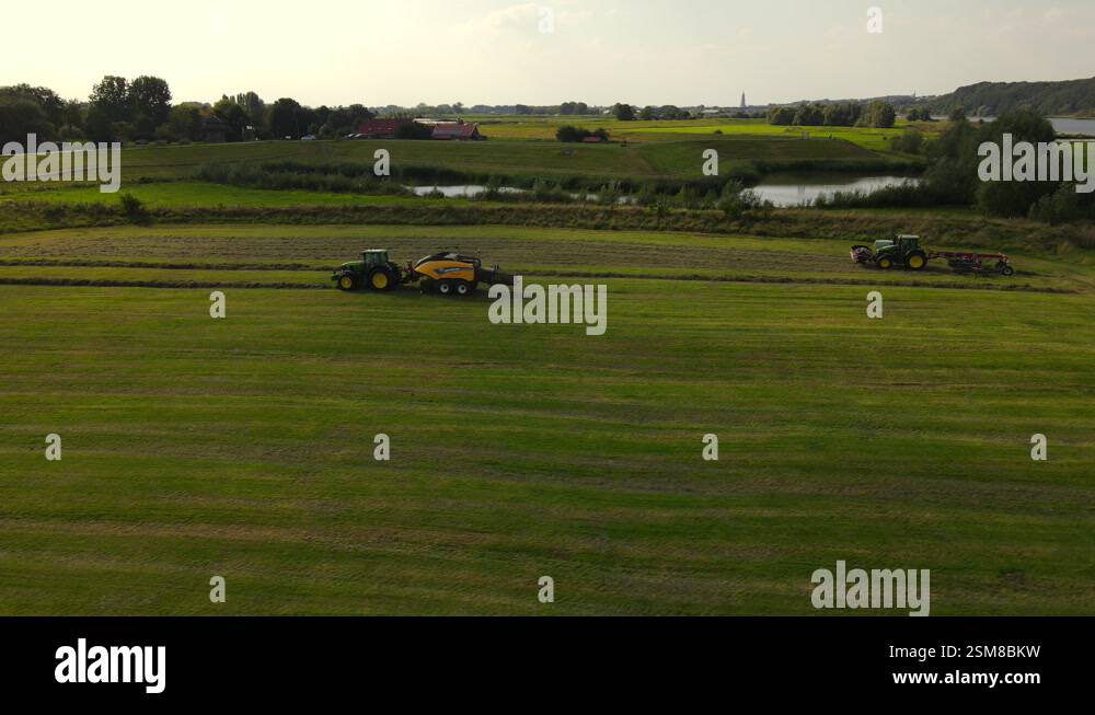 Sideways aerial of tractors producing silo bales during beautiful ...
