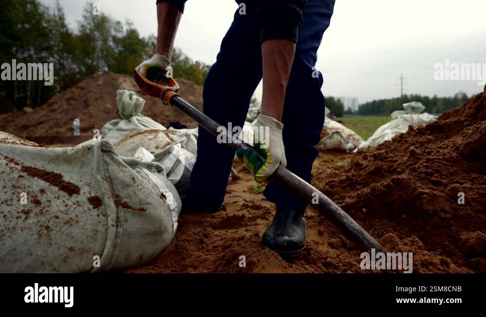 construction worker digging ground and loading to bags, details view ...