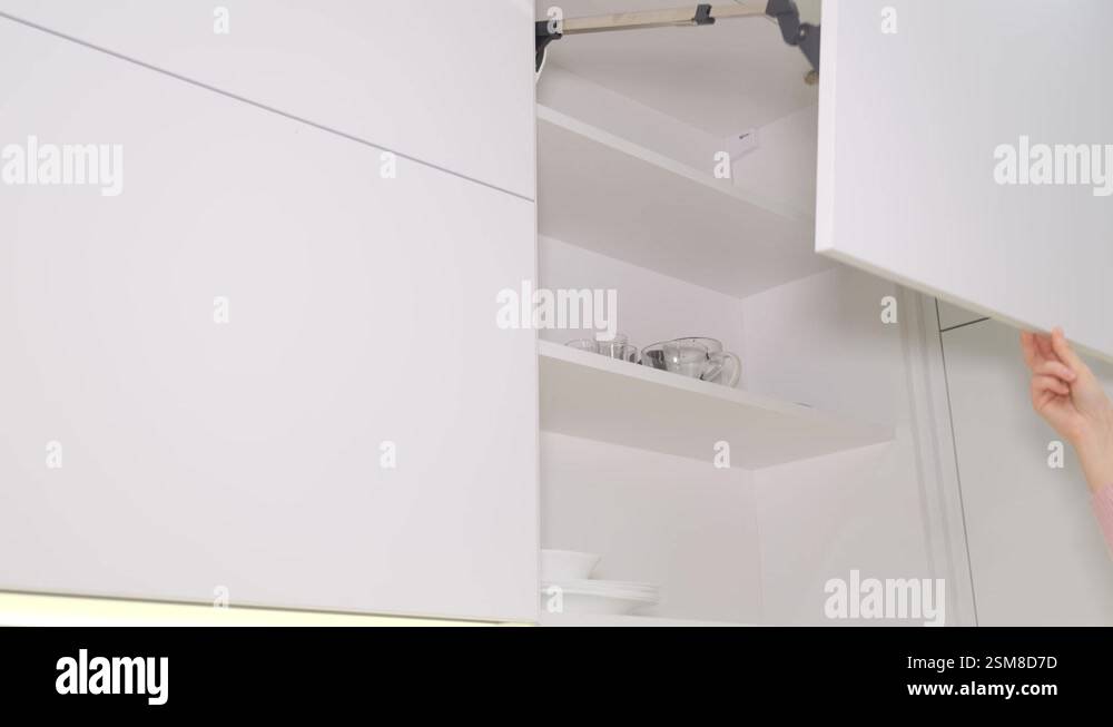 A woman opens a bedside table in a kitchen set. Use of a kitchen ...