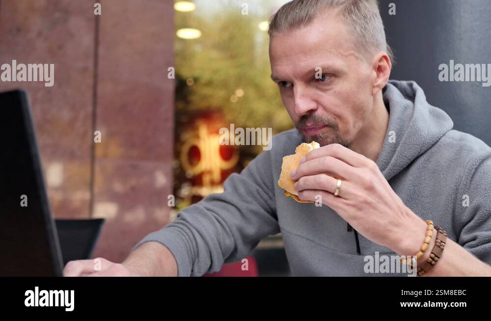 Portrait of a young hungry stylish man who is simultaneously greedily ...