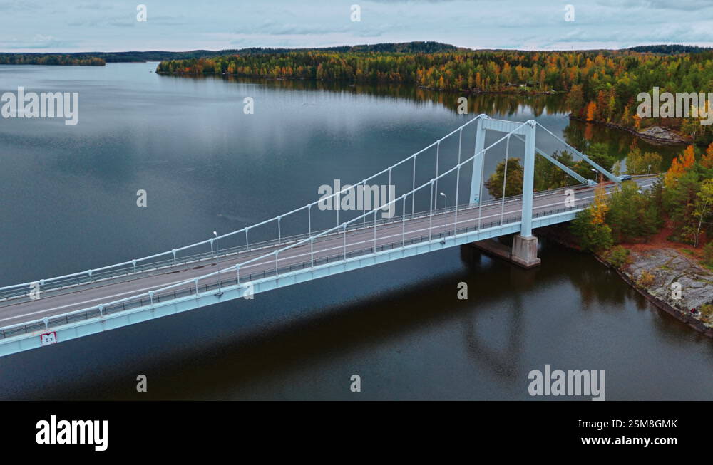 Slow motion orbiting shot of a suspension bridge crossing a cool body ...