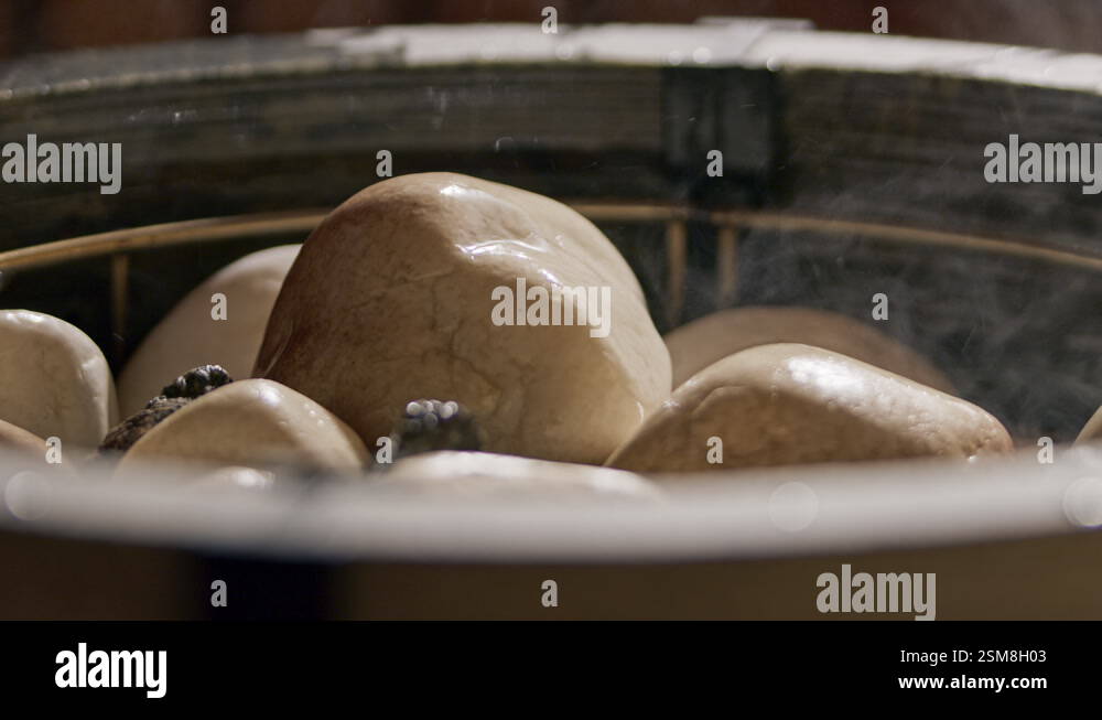 Throwing water on the sauna stones in the sauna stove, creating steam ...