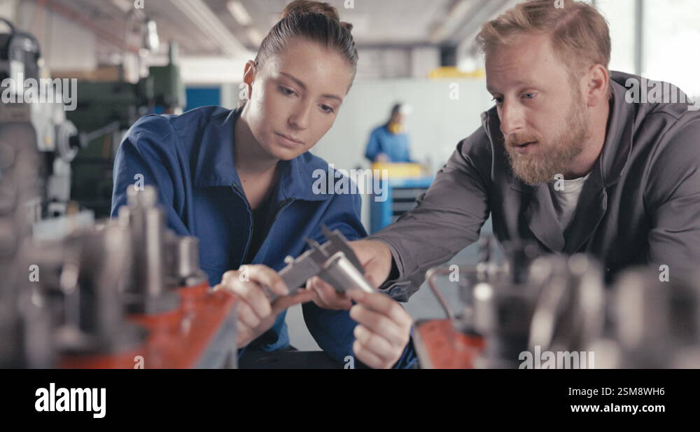 Master explaining apprentice how to measure drill parts with caliper ...