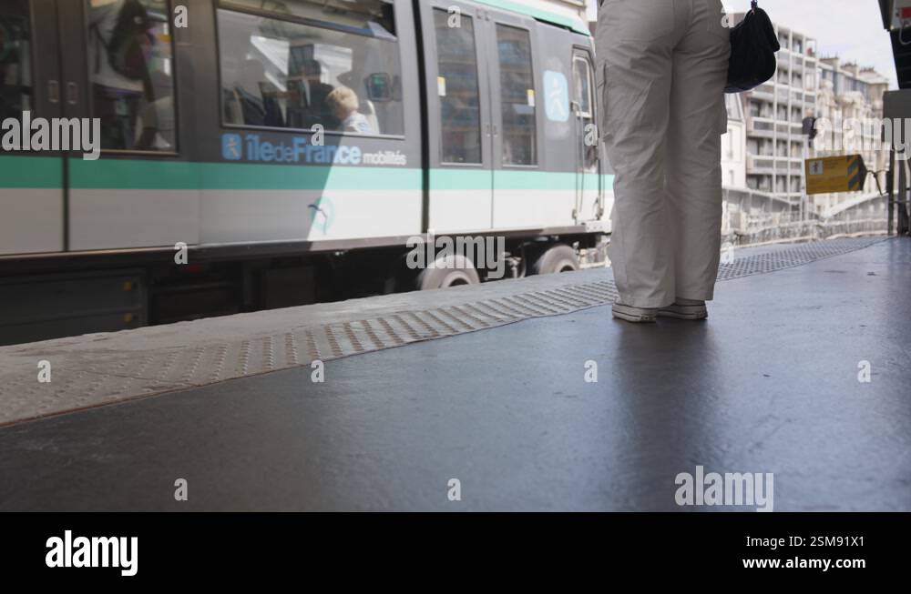 Female standing on train platform waiting as Paris Metro arrives at ...