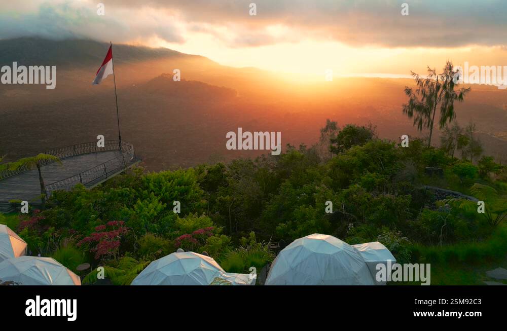 A girl stands by the infinity pool during sunsrise in Glamping camping ...
