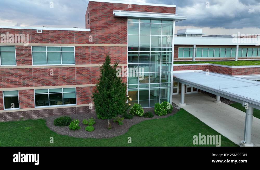 Modern brick school building in USA. Aerial push in on glass stairwell ...