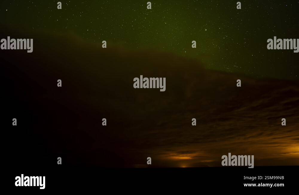 Beautiful time lapse of green northern lights above dark clouds with a ...