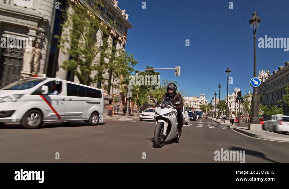 Rolling shot man riding Ducati motorcycle on Gran Via street of Madrid ...