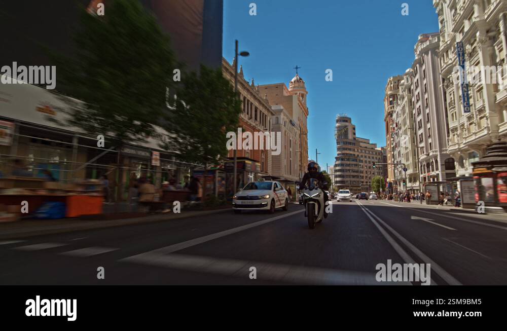 Rolling shot man riding Ducati motorcycle on Gran Via street of Madrid ...