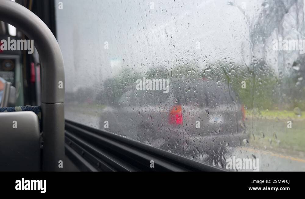 Window with raindrops on a bus driving through the city streets on a ...