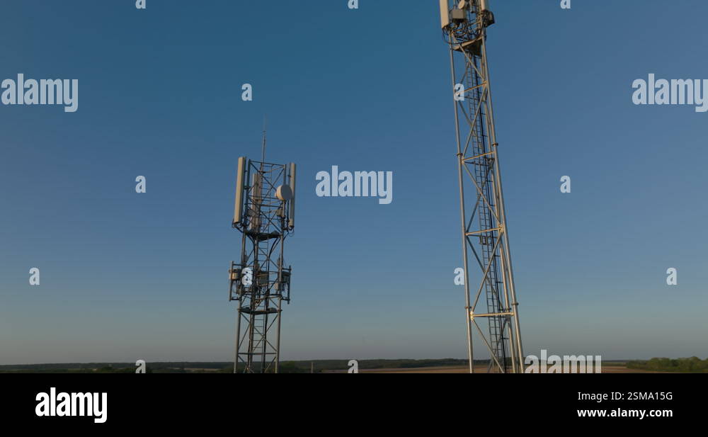 Two cellular towers in the middle of farmland with sky background ...