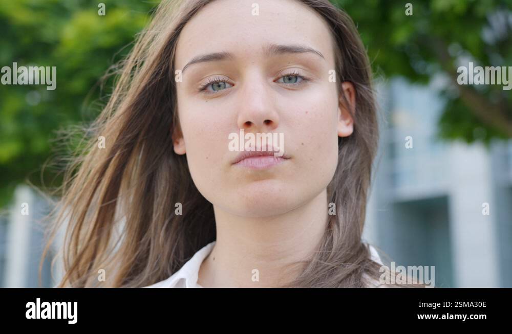 Pretty female with serious face expression looking straight into camera ...