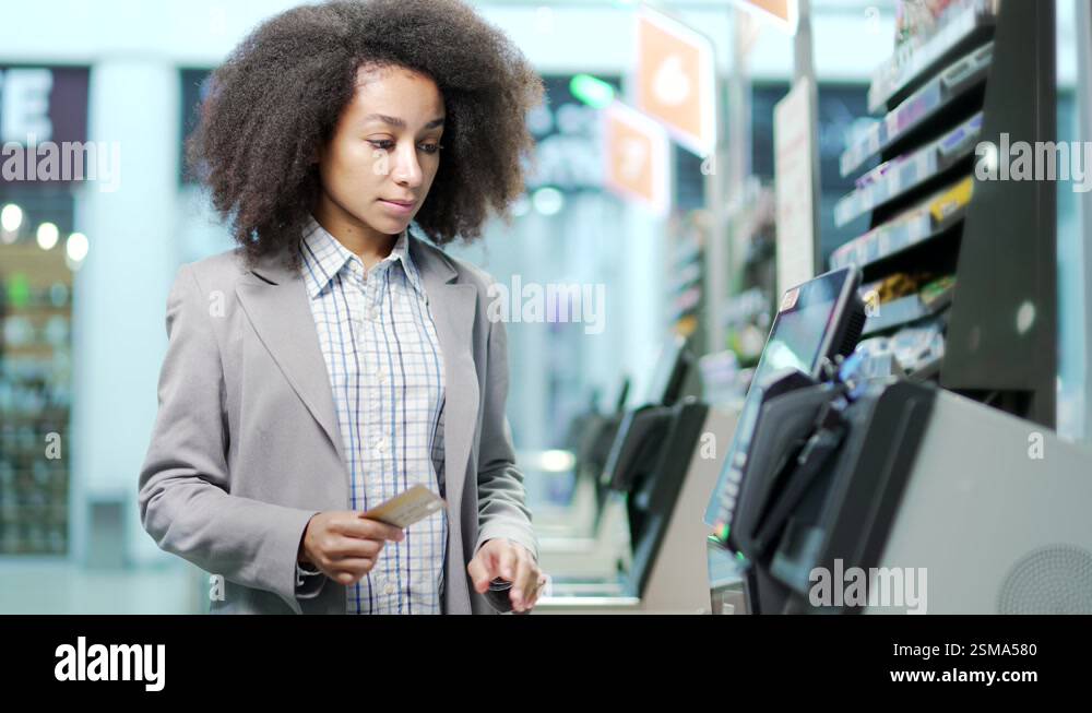Female shopper using a self-service cashier checkout in a supermarket ...