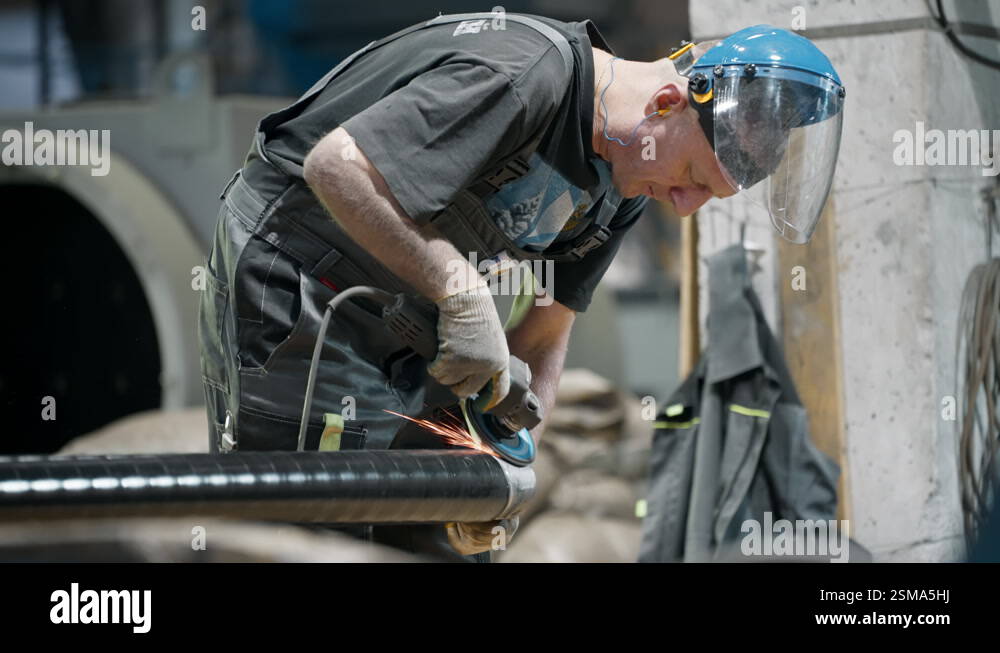 Industrial worker using modern grinding equipment to scrape metal from ...