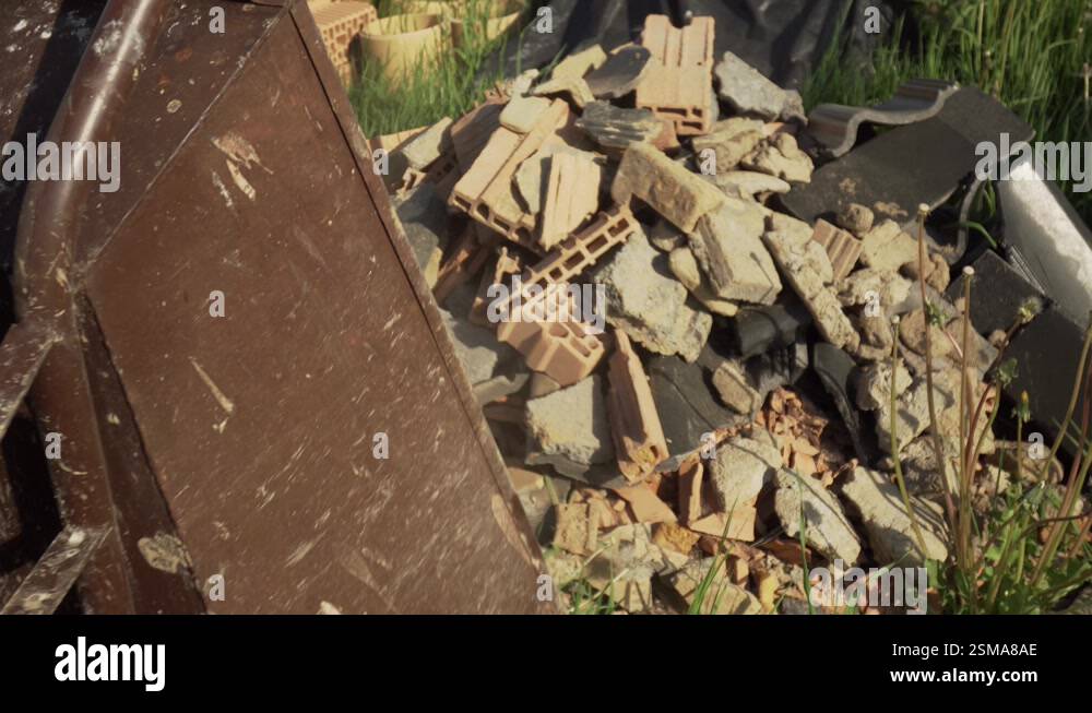 Static shot of person unloading wheelbarrow with rocks and garbage on ...