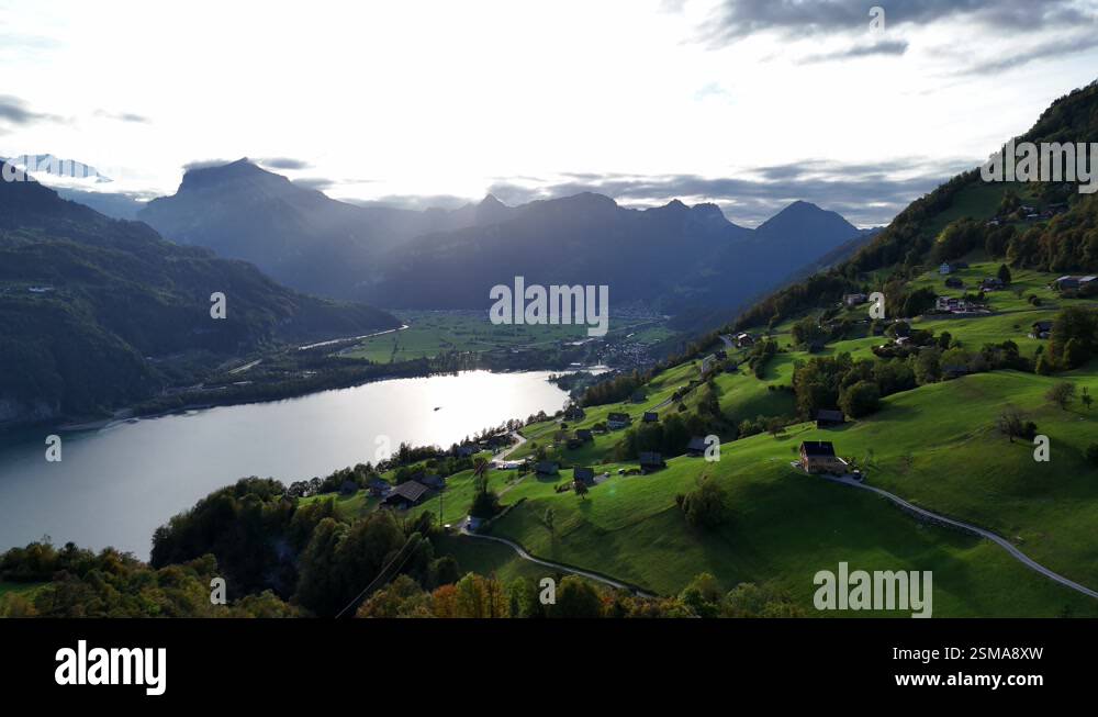 Sideways aerial pan over majestic alpine valley, mirror-like lake below ...