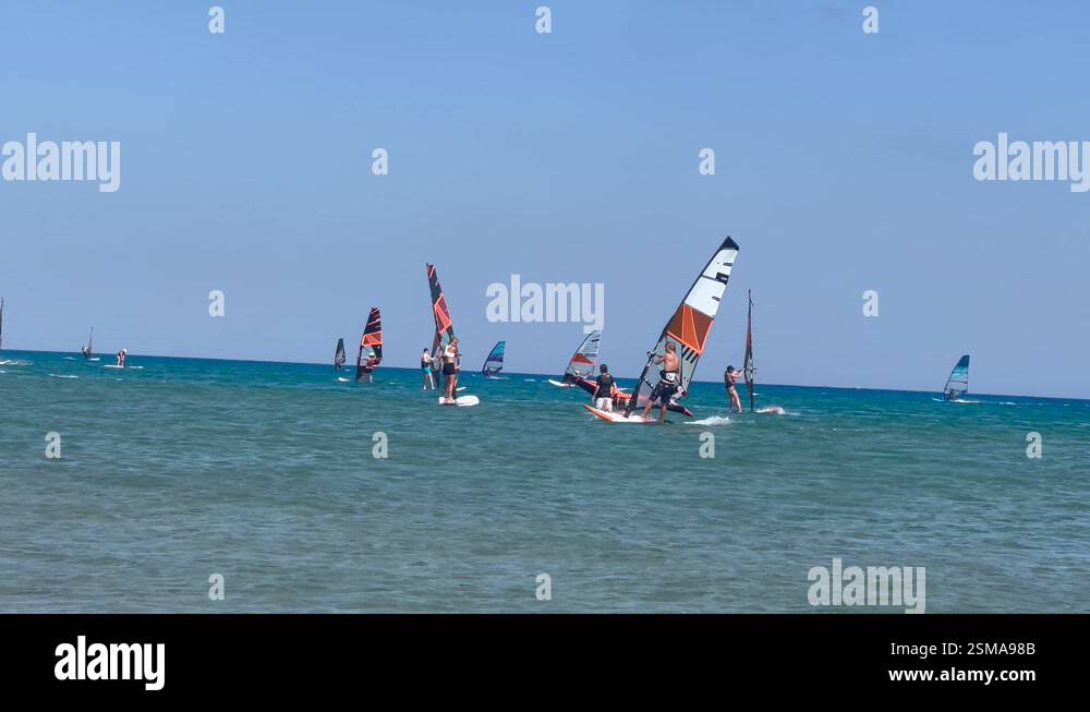 Crowded ocean with many windsurfer holding their sail, dutch angle ...