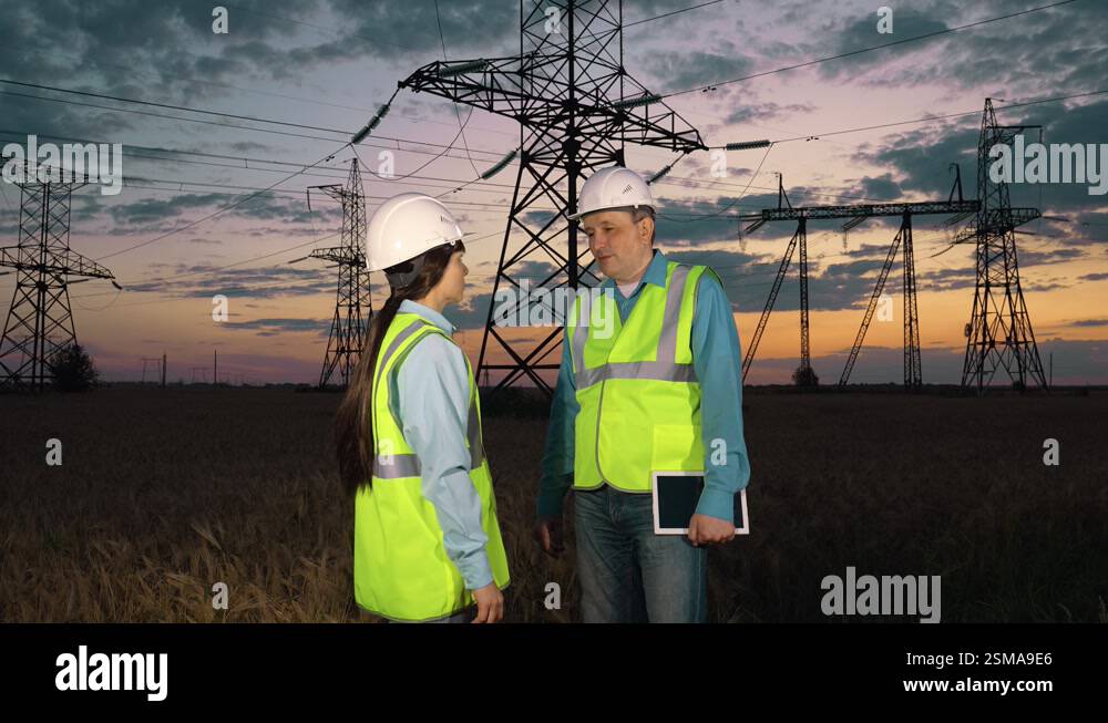 Electricians study development plan on tablet walking past power ...