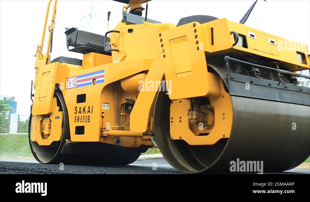 Workers compact the asphalt using a rolling machine, tandem roller ...