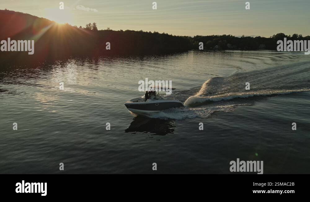 Aerial sunset shot with a boat driving on a lake. Lake Winnipesaukee ...