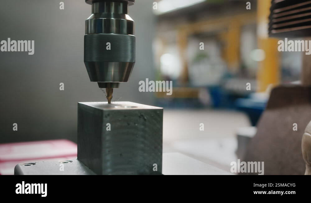 A short drill bit working on a block of metal in a car production ...