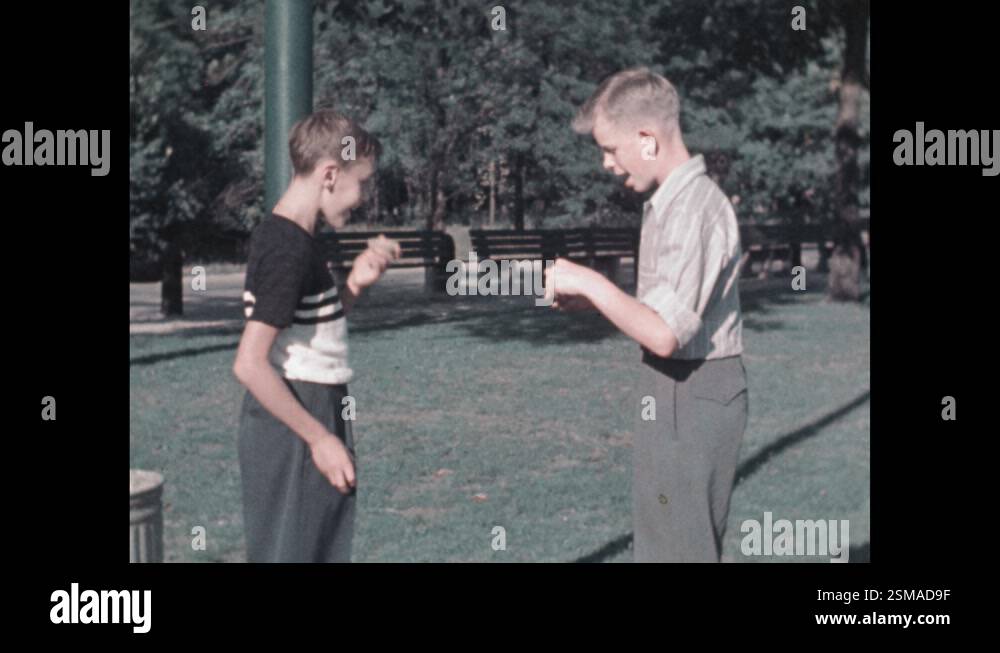 1950s: Park. Boy takes fruit. Boys speak. Boy splits fruit and shares ...