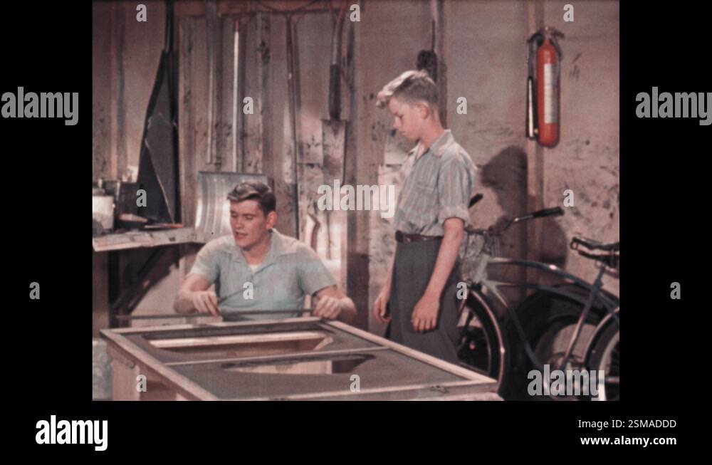 1950s: Garage. Brothers speak. Teenage boy works on window screen. Boy ...