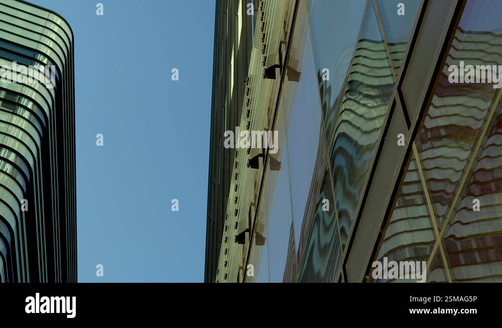 Close-up, angled view of a building's reflective glass facade, showing ...