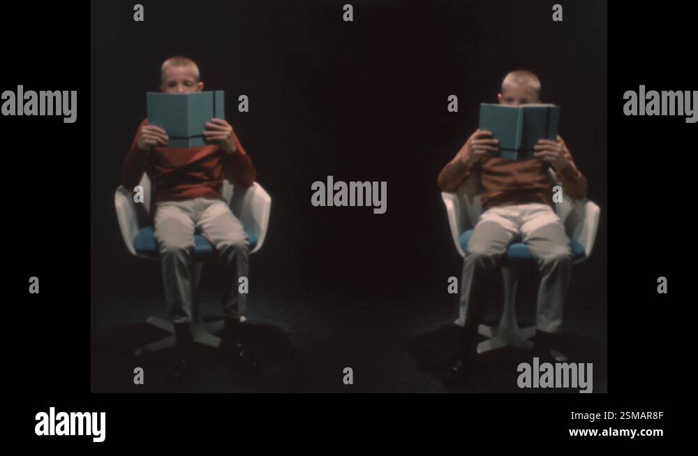 1970s: Two boys sit side by side in chairs with books held in front of ...