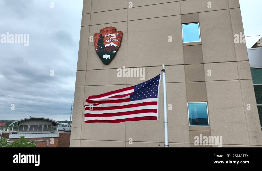 American flag waving at NPS building. National Park Service emblem ...