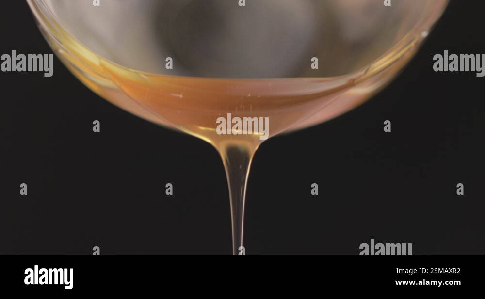 Honey dropping and spilling with a black background in 4K resolution ...