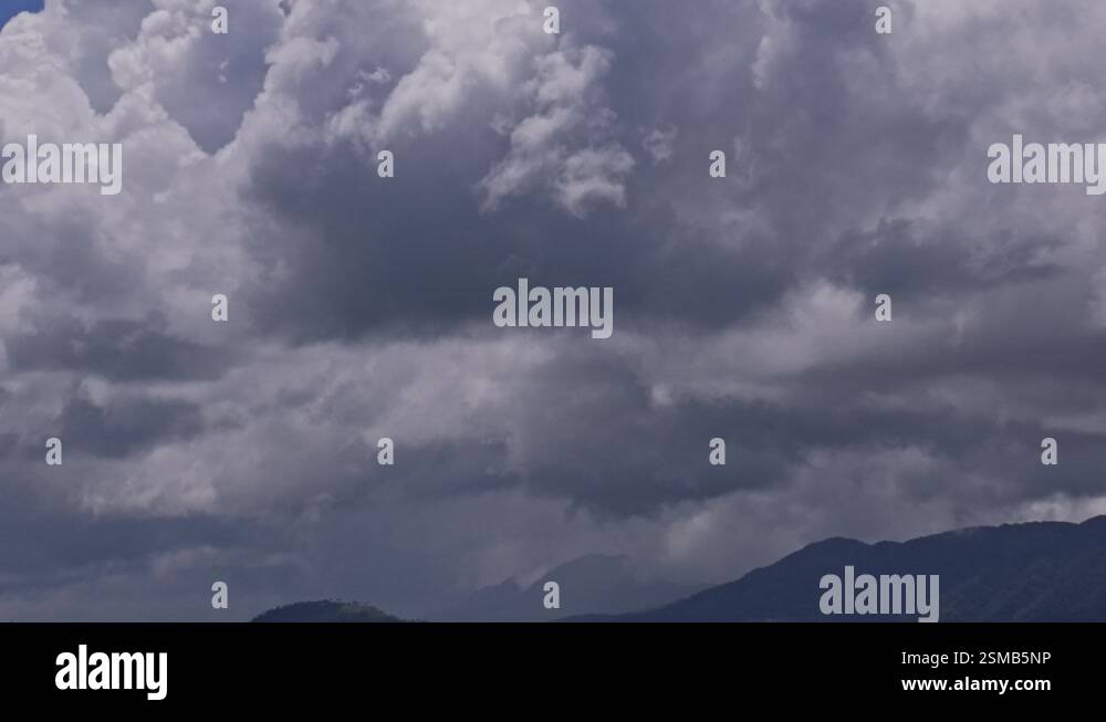 Thick dark grey storm clouds over a dark mountains landscape. Zooming ...