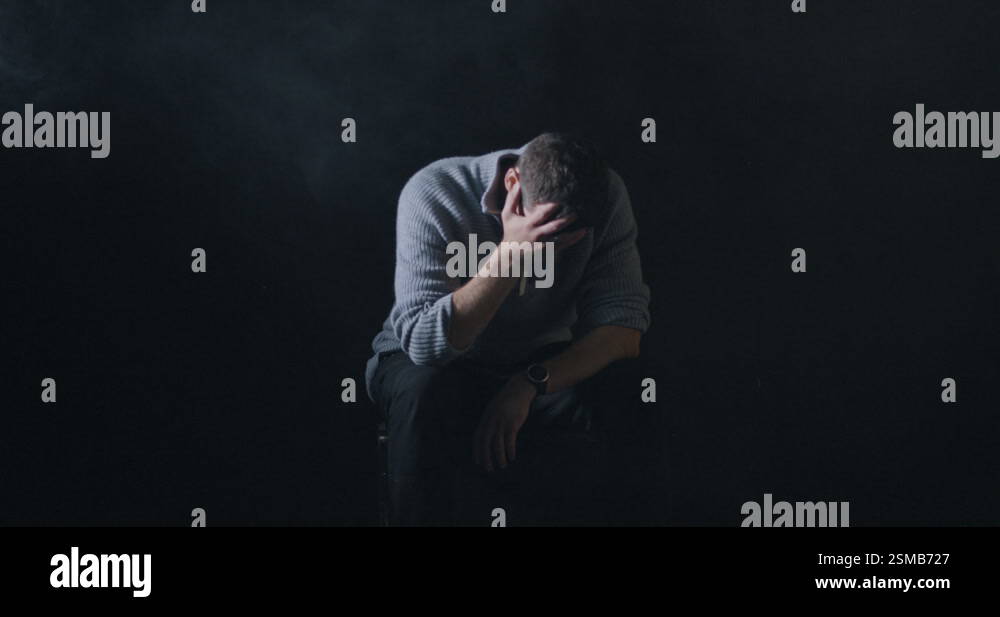 Sad man on black background studio with smoke behind, medium shot ...