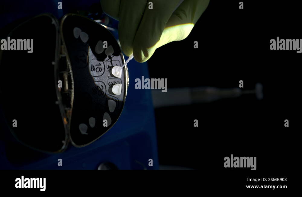 Slow motion of a dentist hands applying glue to the inside of a set of ...