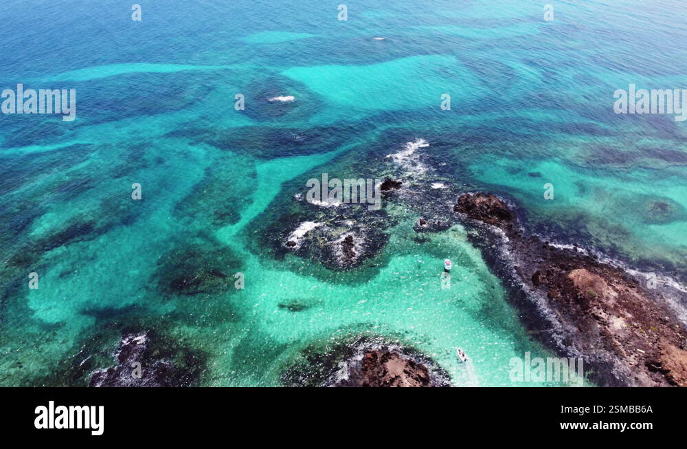 Turquoise waters and small boats surrounding the island of Los Lobos ...