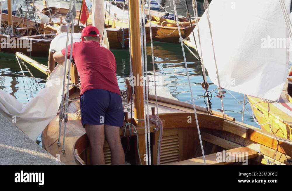 Two men are preparing an old sailing yacht to sail from the shore Stock ...