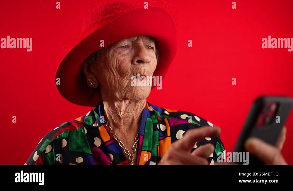 Toothless elderly senior old woman with wrinkled skin looking at phone ...