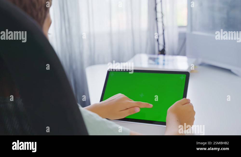 Close up kids hands holding and tapping on a tablet with green screen ...