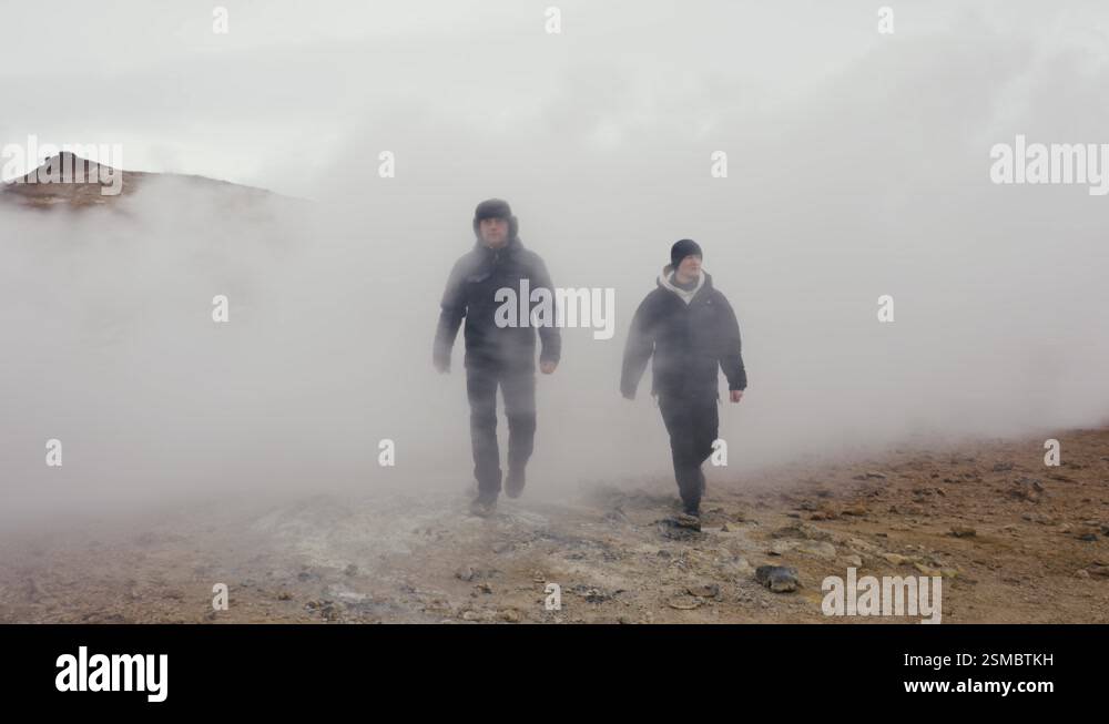 Father and son walk through dense steam cloud at Geothermal area ...