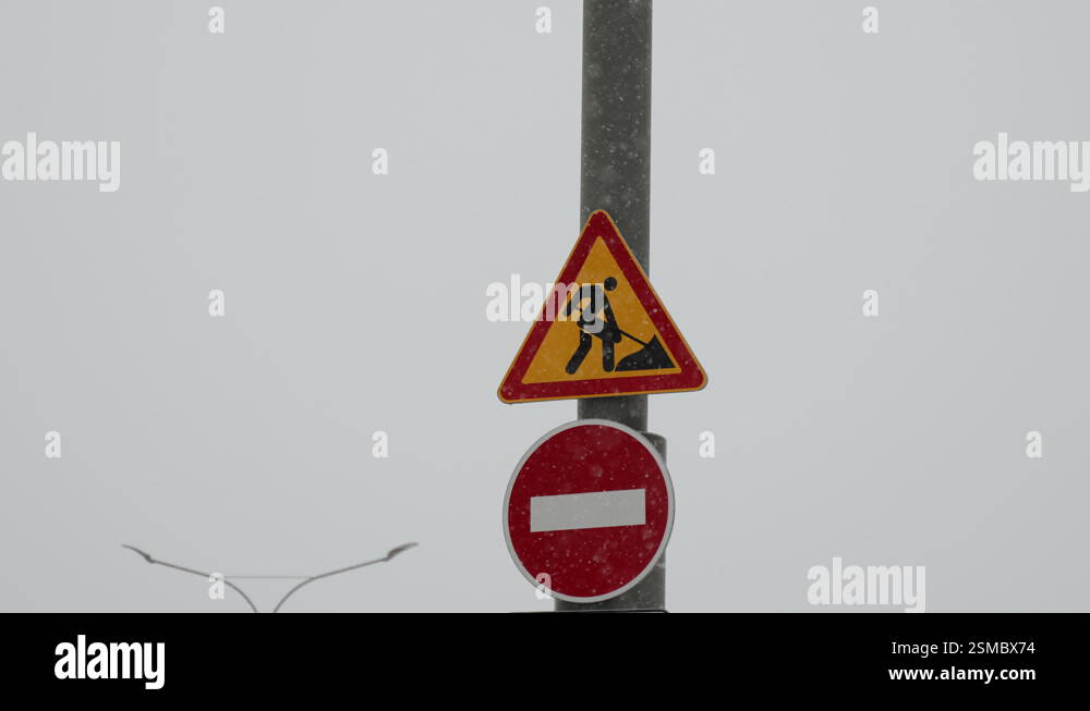 No entry and road work road signs on concrete pillar in winter during ...