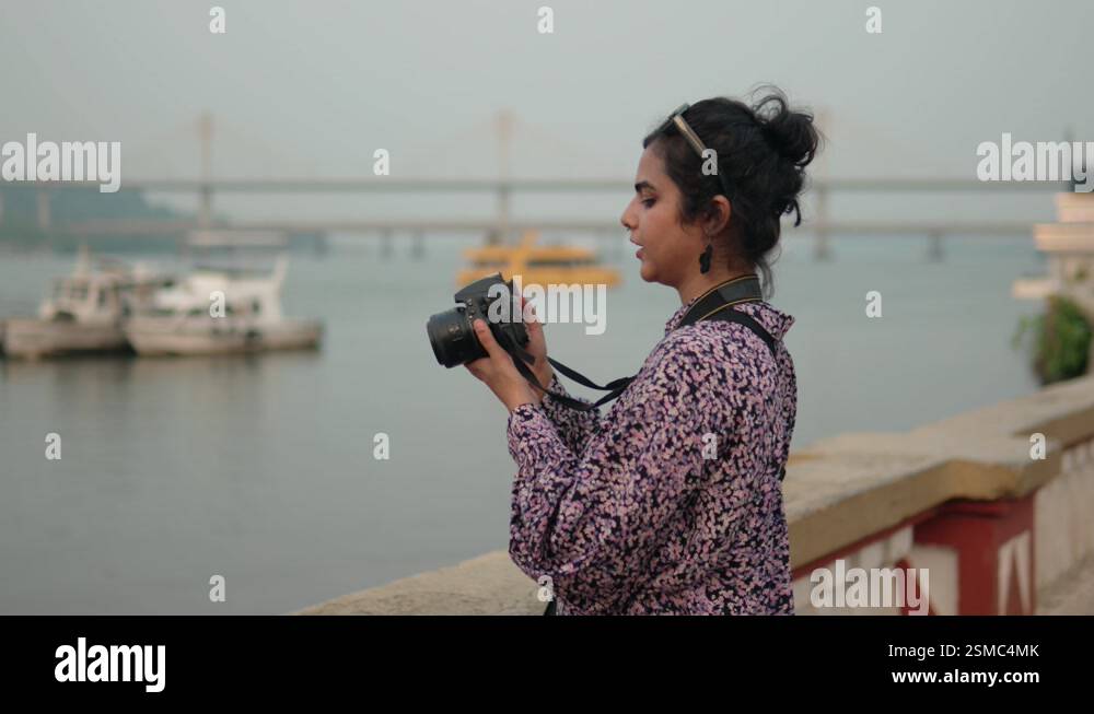 A tourist woman stands in front of a river, skillfully capturing ...