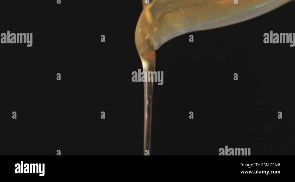 Honey dropping and spilling with a black background in 4K resolution ...