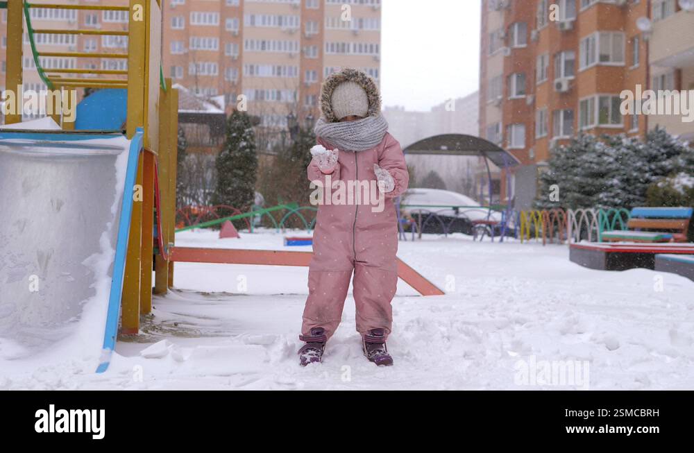 5 years old girl enjoying winter day on a fenced sports ground. She ...