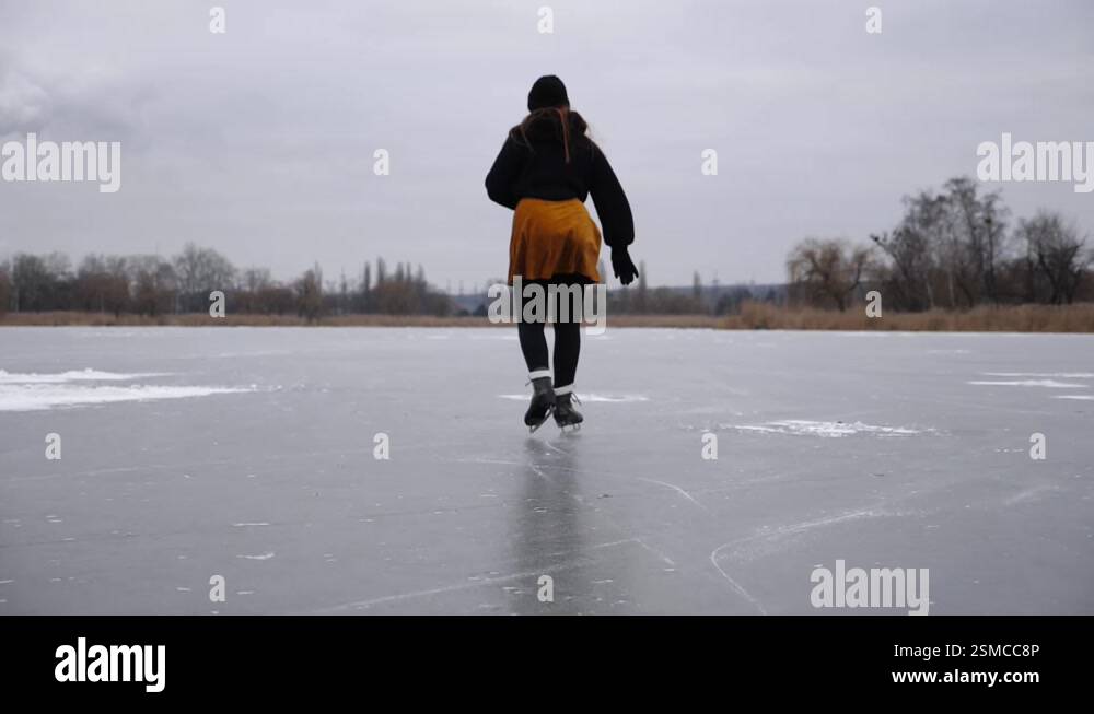 Lady shot in figure skates sliding on ice surface at nature. Woman ...