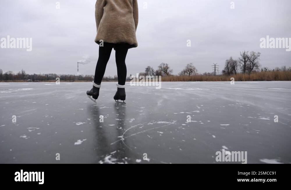 Young woman in fur coat training rotation skills on frozen river. Girl ...