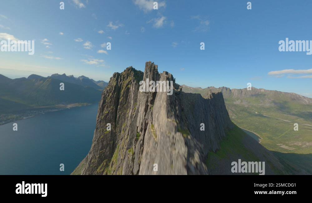Dynamic fpv flight over summit of senja mountain range with valley and ...