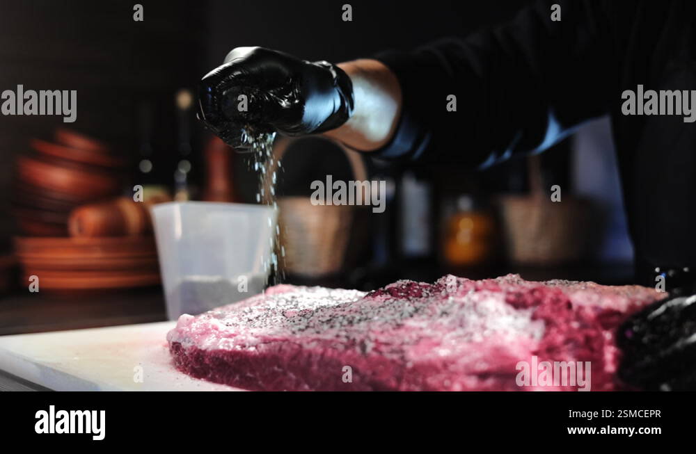 Man chef hand sprinkling salt dry seasonings to farm meat piece at ...
