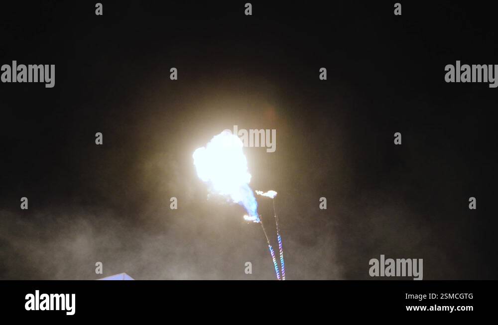 Smoke blows by in the wind as neon lighted antennae shoot tall flames ...