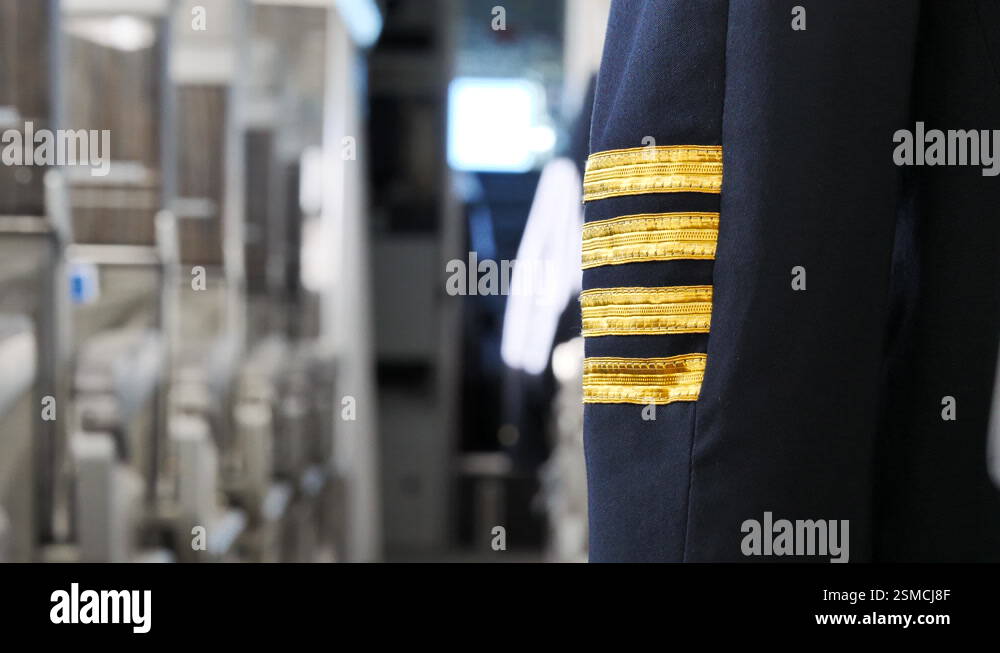 Captains uniform hanging, cabin with pilots in background. Real time ...