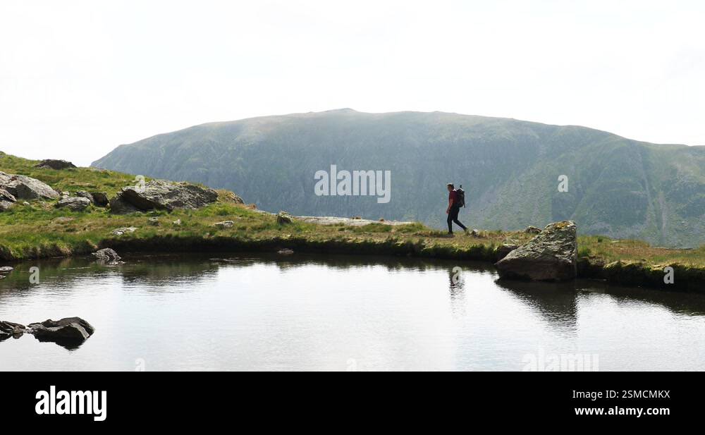 A hiker at Hard Tarn below Nethermost Pike on the Helvellyn range, Lake ...